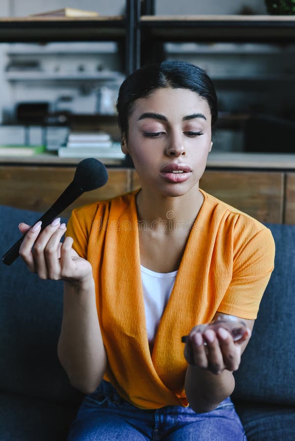 Beautiful Mixed Race Girl In Orange Shirt Applying Face Powder Stock