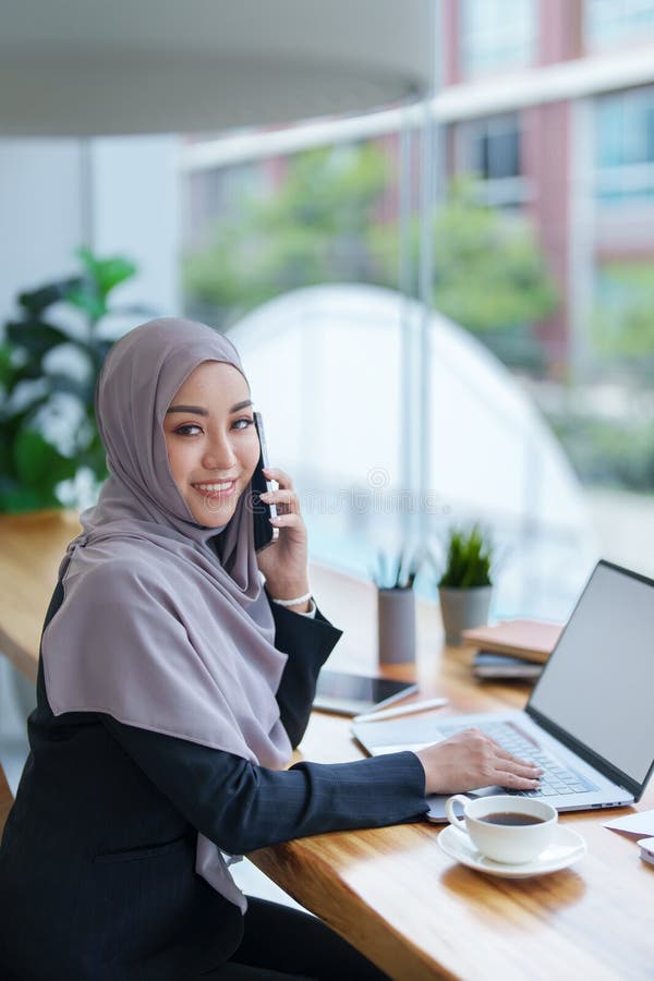 Beautiful Muslim Woman Talking on the Phone and Using Computer on Top ...