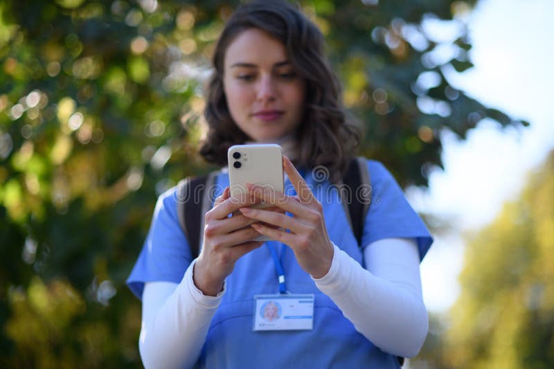 Beautiful Nurse in Uniform Holding Smartphone in Hands, Scrolling ...