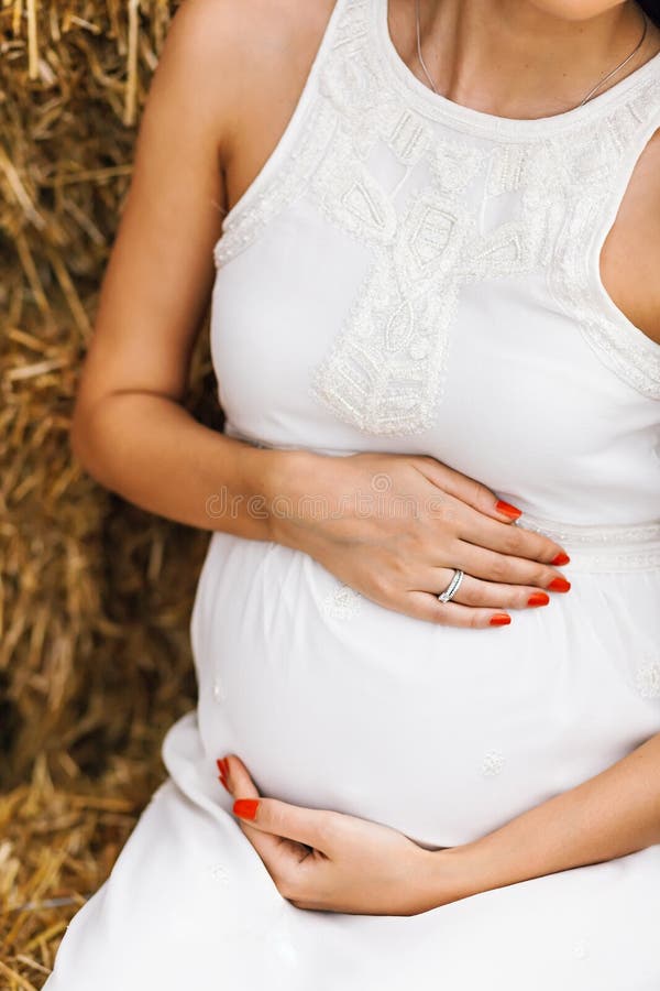 Beautiful Pregnant Woman Dressed In White Dress Touches Her Belly