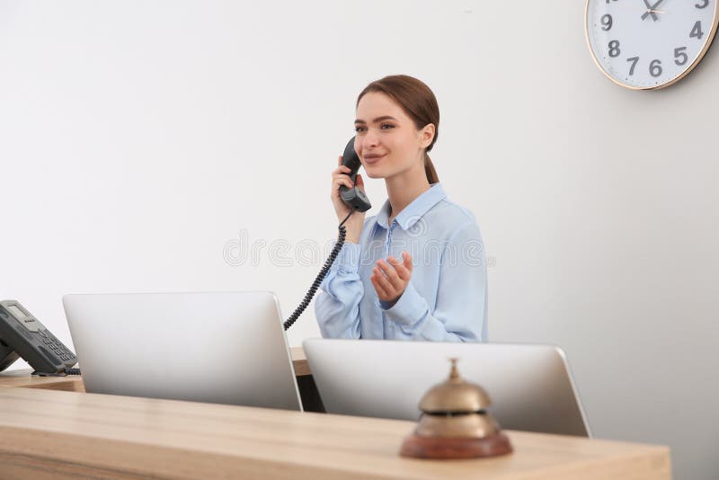 Beautiful Receptionist Talking on Phone at Counter in Hotel Stock Photo ...