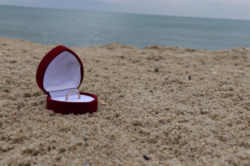 A Beautiful Ring in a Red Box in the Sand on the Beach by the Sea ...