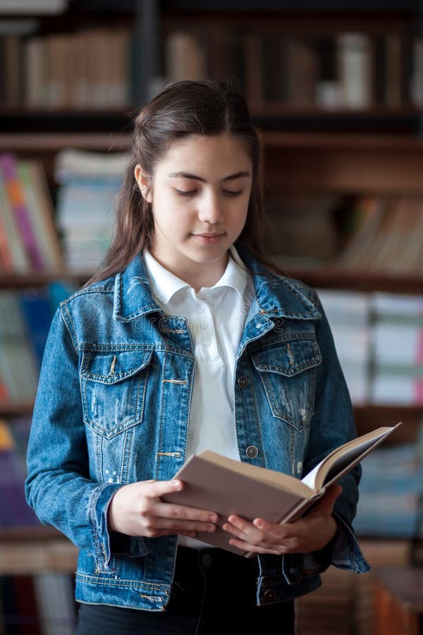 Beautiful Schoolgirl Standing in the Library and Reading a Book Stock ...