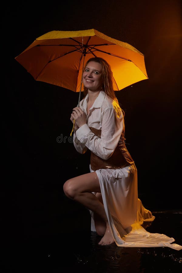 Beautiful Skinny Girl In A Dark Hall With Splashes Of Water And Yellow