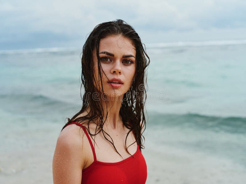 Beautiful Woman In A Red Swimsuit Looks At The Camera On The Ocean