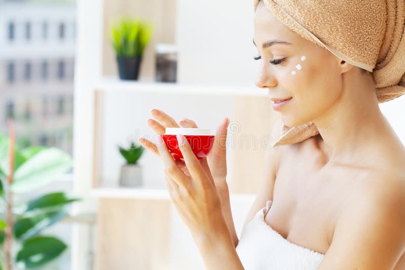 Beautiful Woman Applying Moisturizer Cream On Her Face Stock Image