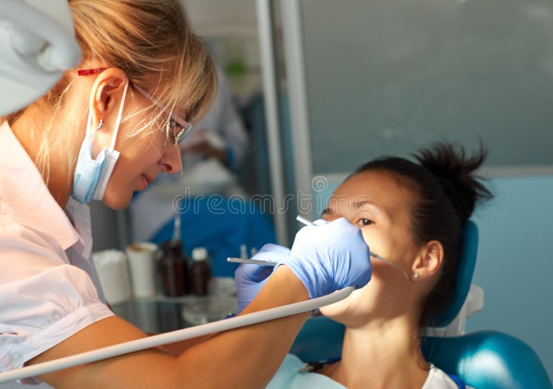 Beautiful Woman Dentist Treating A Patient S Teeth In Dental Office