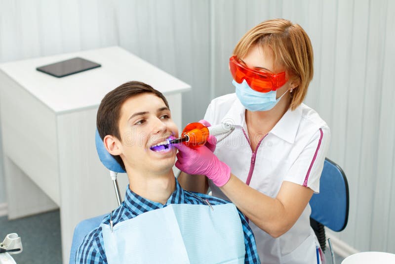 Beautiful Woman Dentist Treating A Patient Teeth In Dental Office Stock