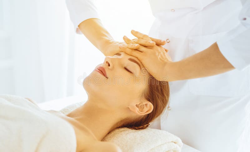 Beautiful Woman Enjoying Facial Massage With Closed Eyes In Sunny Spa