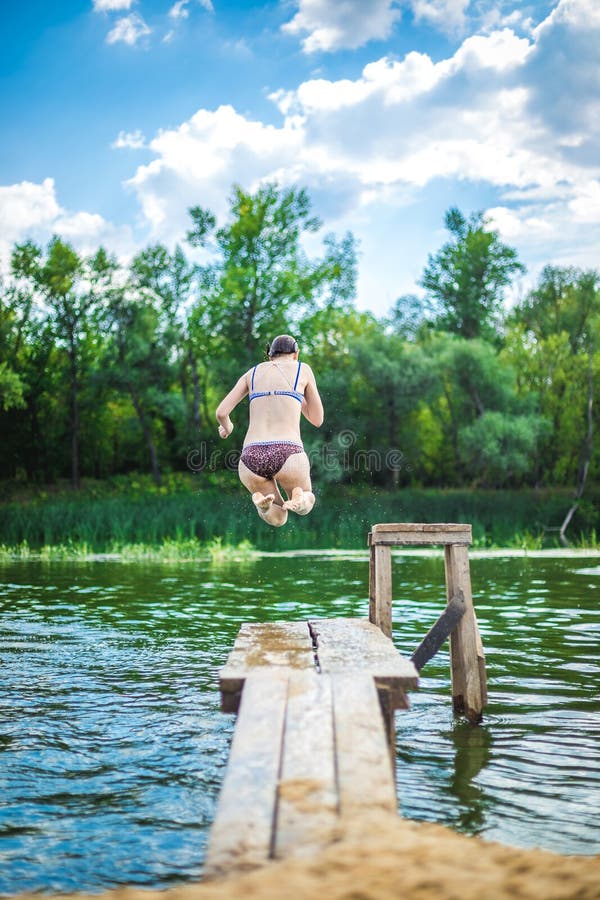 A Beautiful Woman Jumping into the Water from a Pier Stock Photo ...