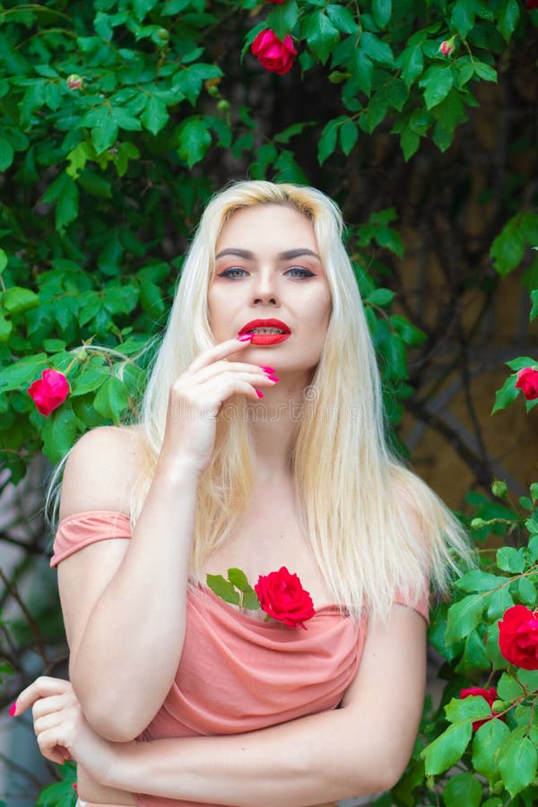 Beautiful Woman With Long Blonde Hair And Red Lips Wearing Pink Clothes