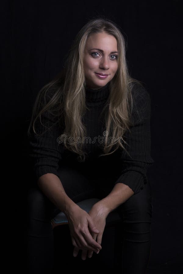 Beautiful Woman Portrait In Low Light Sitting On Brown Leather Sofa