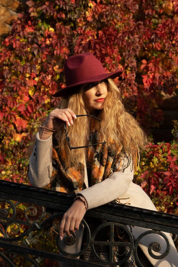 A Beautiful Woman in a Red Hat and Coat Stands at the Railing in Front ...