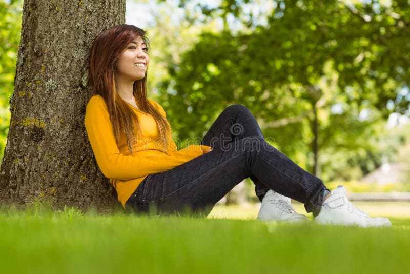 Beautiful Woman Sitting Against Tree in Park Stock Photo - Image of ...