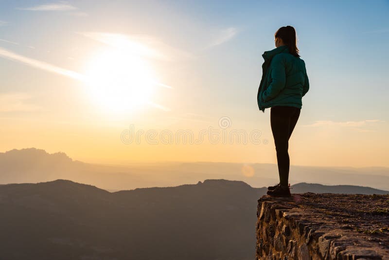 Beautiful Woman Standing on an Edge during Sunset with Mountains on the ...