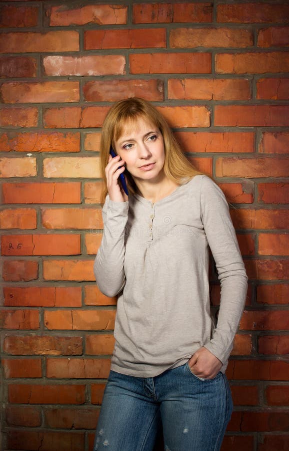 Beautiful Woman Using High Tech Smartphone Against Brick Wall. Stock ...