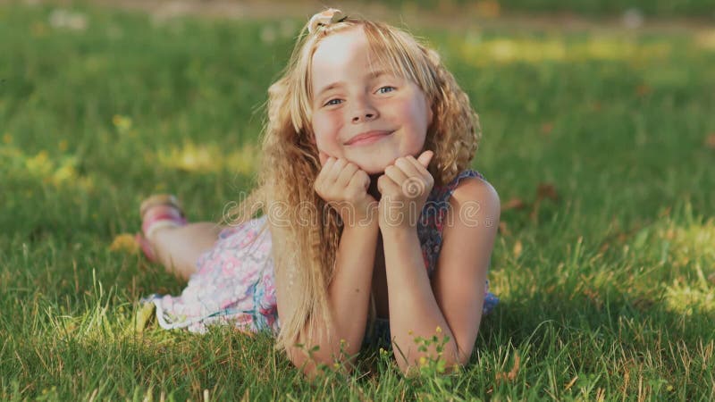 Beautiful Young Blonde Girl Lying On A Field Green Grass Outdoors