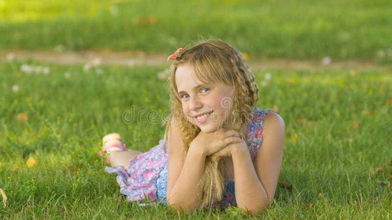 Beautiful Young Blonde Girl Lying On A Field Green Grass Outdoors