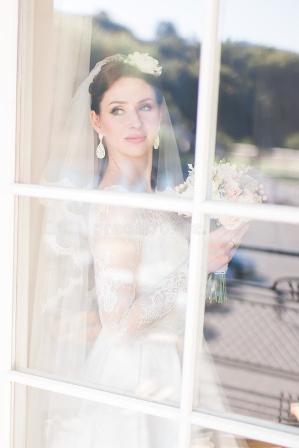 Beautiful Young Bride I with Bridal Bouquets Looking through the Window ...