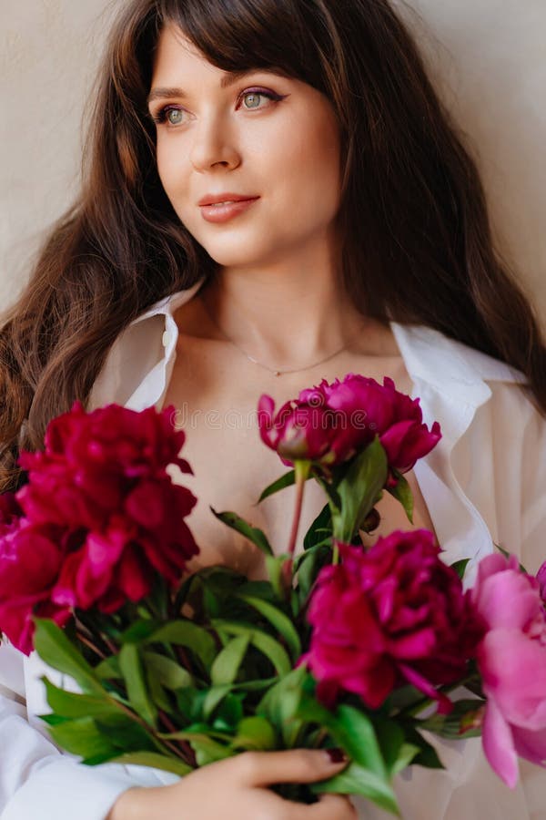 A Beautiful Young Brunette Woman In A White Shirt With A Bouquet Of