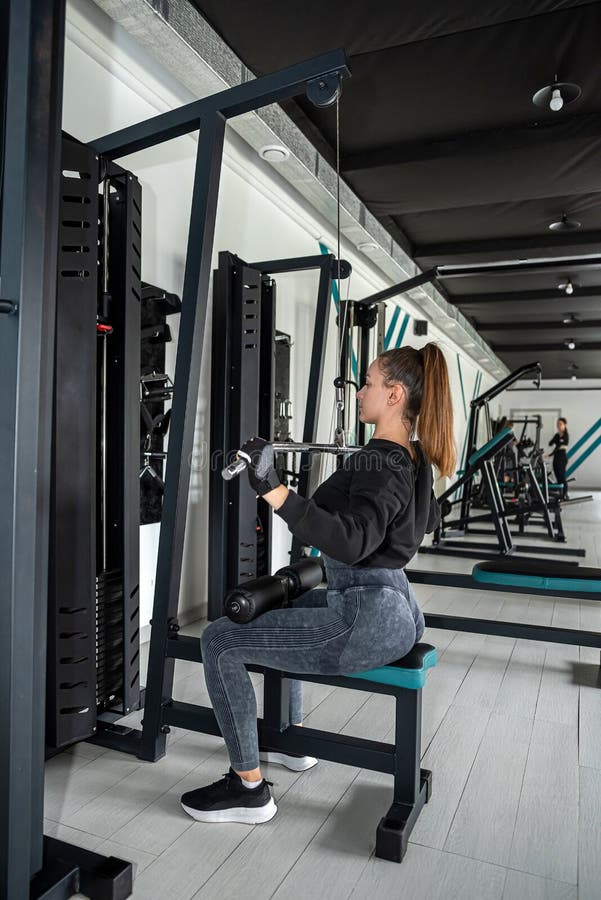 Beautiful Young Client is Doing Exercises on the Simulator for Back ...