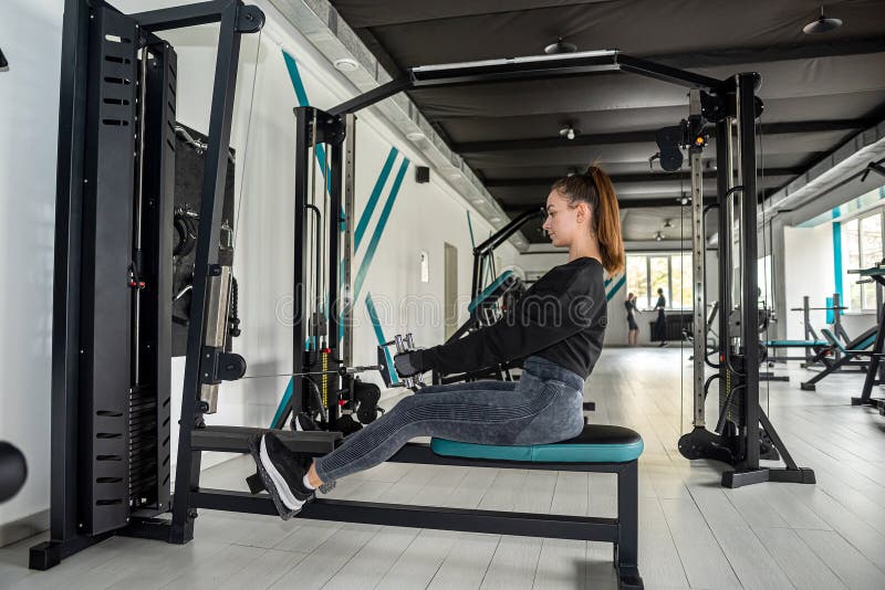 Beautiful Young Client is Doing Exercises on the Simulator for Back ...