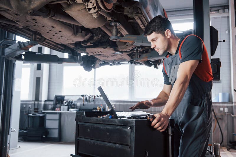 Beautiful Young Guy. Man at the Workshop in Uniform Using Laptop for ...