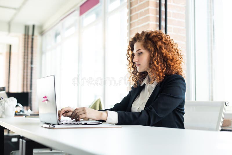 Beautiful Young Red Haired Woman In A Business Suit Works In An Office