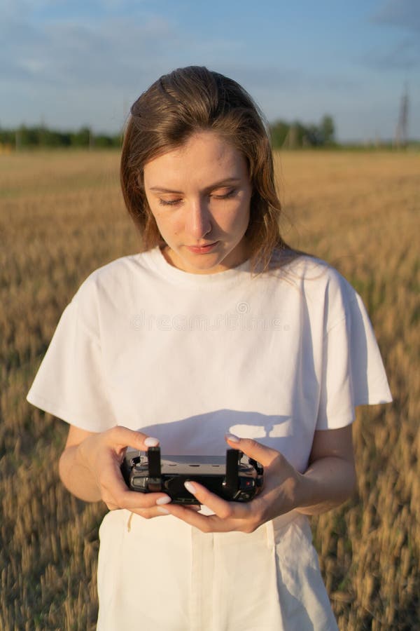 A Beautiful Young Woman in a Field Controls a Drone in Flight. Control ...