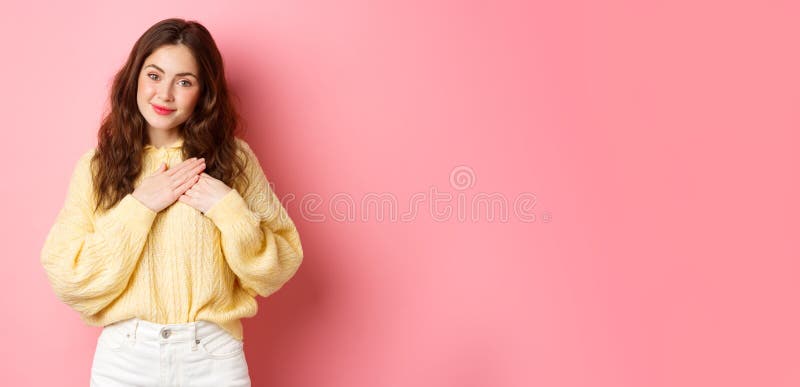 Beautiful Young Woman With Kind Smile Holding Hands On Heart And