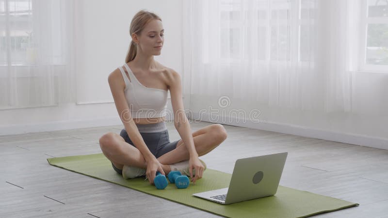 Beautiful Young Woman Sitting on Mat and Holding Dumbbell while Using ...