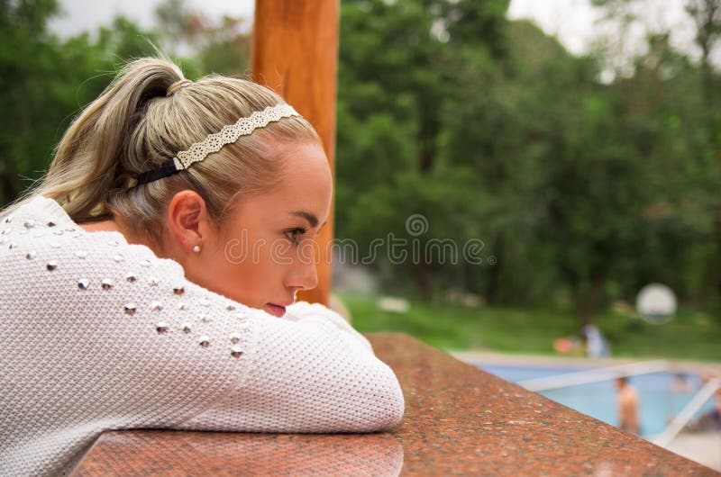 Beautiful Young Woman Sitting by the Pool Looking Pensive Stock Photo ...