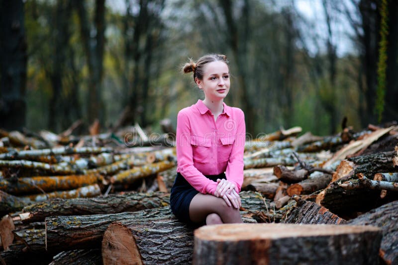 Beautiful Young Woman Sitting on Stack of Felled Tree Trunks in the ...