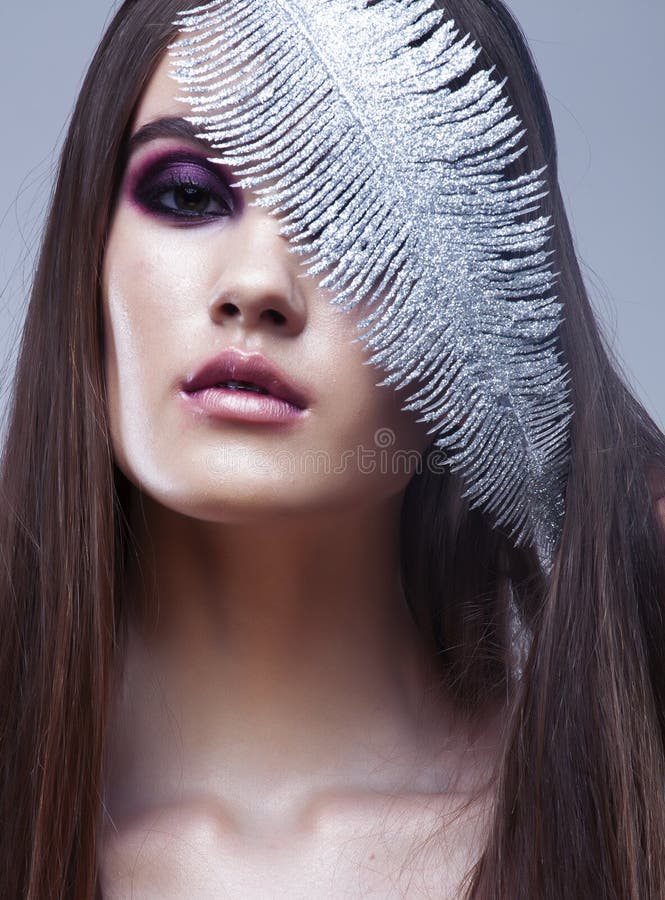 Beauty Brunette Young Girl With Fashion Makeup And Silver Feather