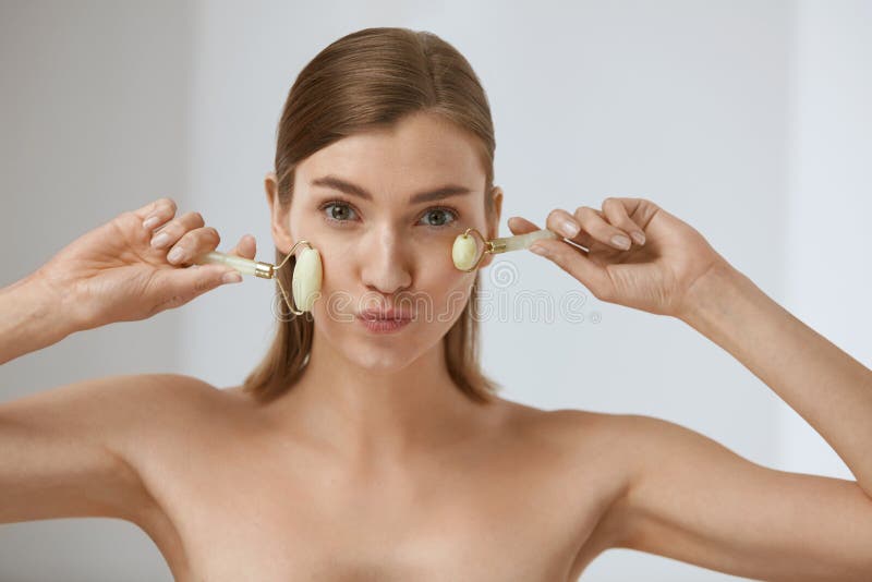 Beauty Face Care Woman Doing Facial Massage With Jade Rollers Stock