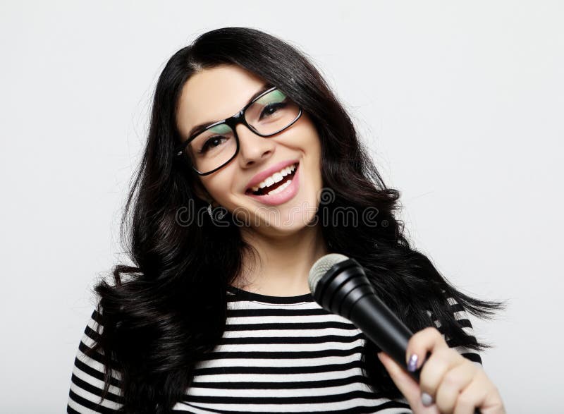 Beauty Model Girl Singer with a Microphone Over Light Grey Background ...
