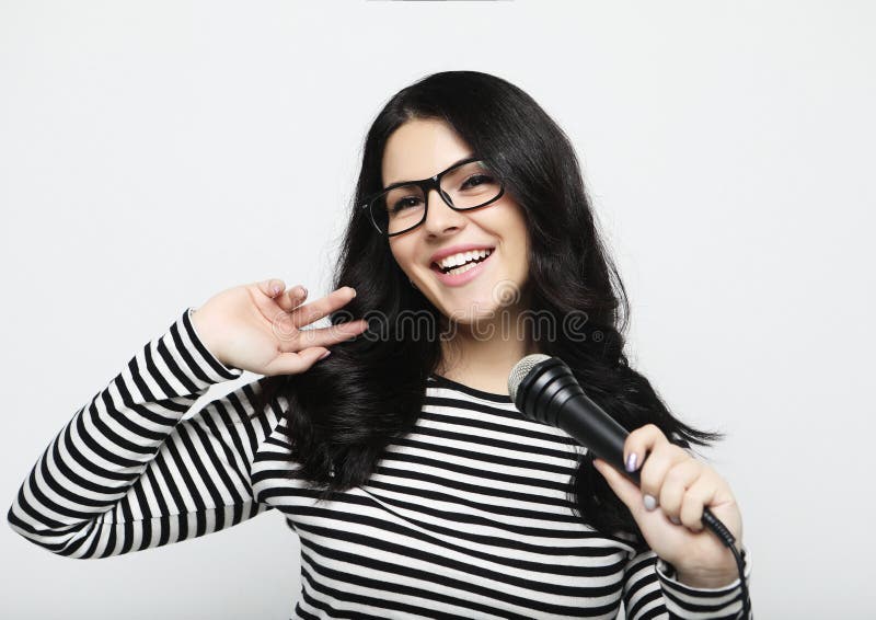 Beauty Model Girl Singer with a Microphone Over Light Grey Background ...