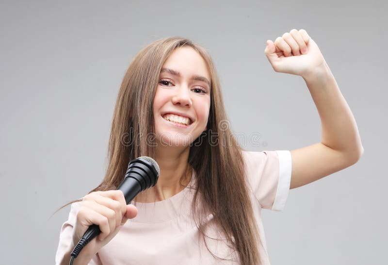Beauty Model Girl Singer with a Microphone Over Light Grey Background ...