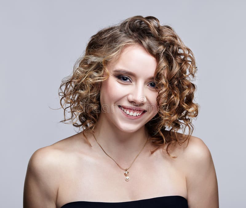 Beauty Portrait Of Young Smiling Woman With Curly Hair On Gray