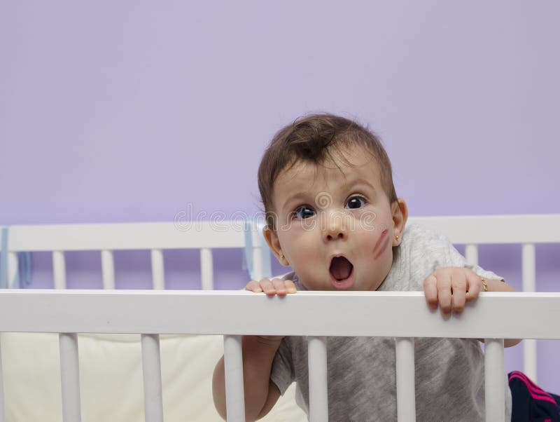 Bebê Do Divertimento Com Marca Do Beijo No Berço. Imagem de Stock ...