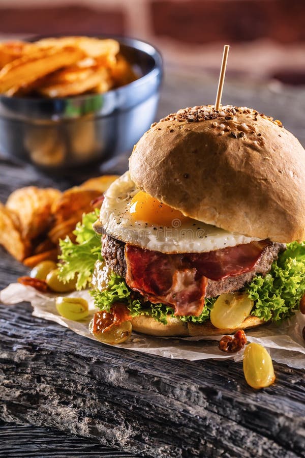 Beef Burger with Fried Egg, Bacon, Lettuce, Potato Wedges and Grapes in ...