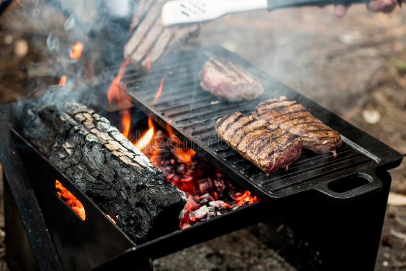 Beef Steaks Grilling on a Cast Iron Plate on a Camp Fire. Campfire ...