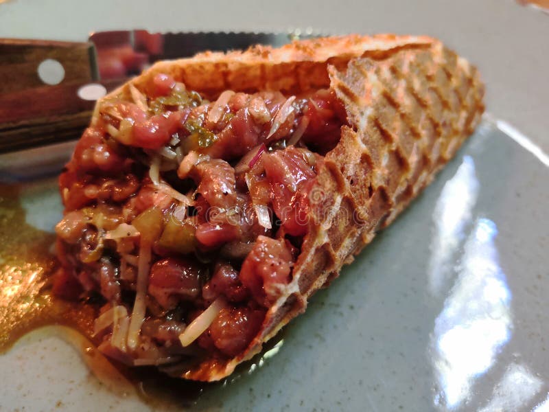 Beef Tar-tar with Sliced Onions and Pickles in a Round Waffle on a ...