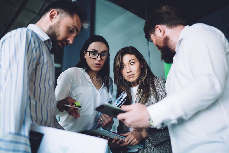 Group of Astonished Office Workers Having Conversation while Using ...