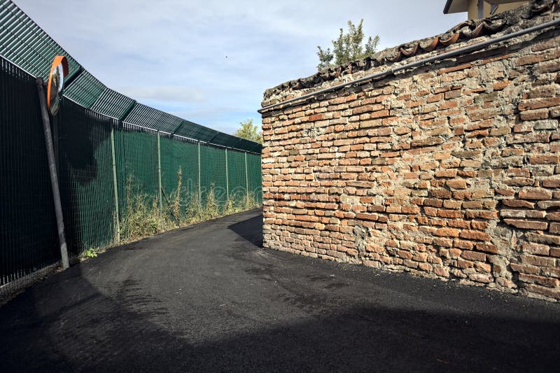 Bend in a Gravel Path between a Fence and a Brick Wall on a Cloudy Day ...