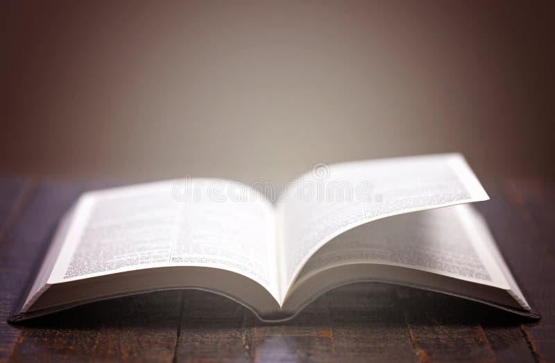 A Bible Open on a Rustic Wooden Table with Pages Blowing Open Stock ...
