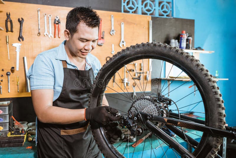 A Bicycle Mechanic in Apron Holds the Rear Mech while Fixing Problems ...