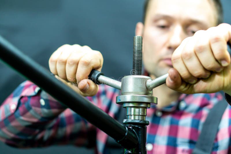 A Bicycle Mechanic on a Black Background Holds in His Hand a ...