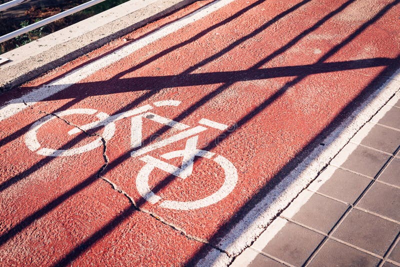 Bicycle Sign on a Red Bike Path Under a Shadow of a Fence Stock Photo ...