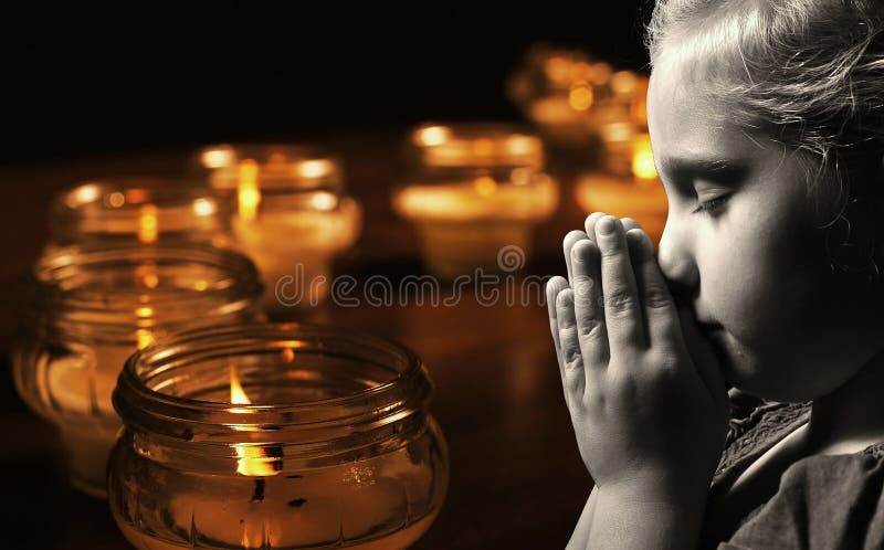 Biddend kind met kaarsen stock afbeelding. Image of handen - 49973415
